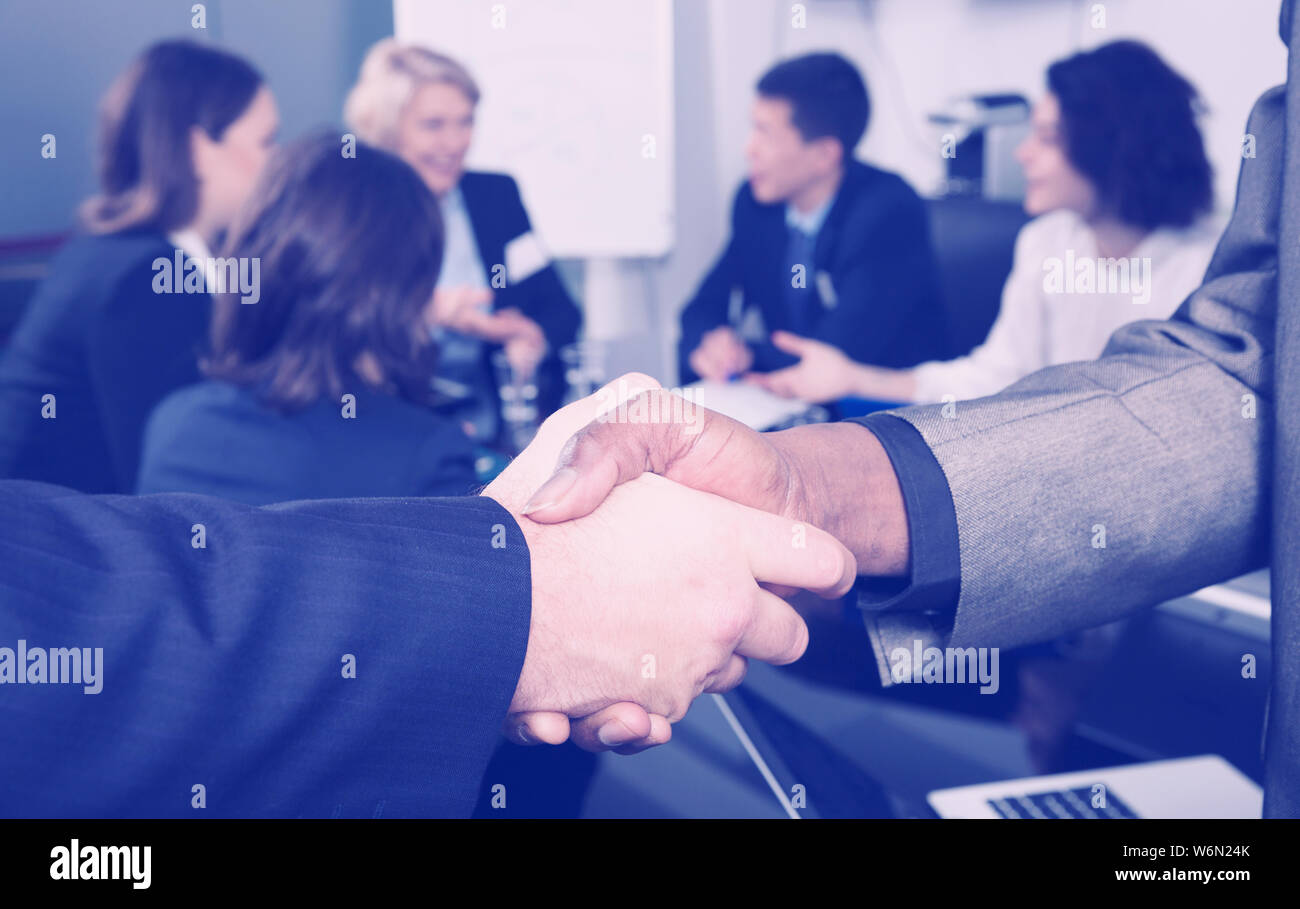 Closeup of international businessmen handshake on blur meeting room ...