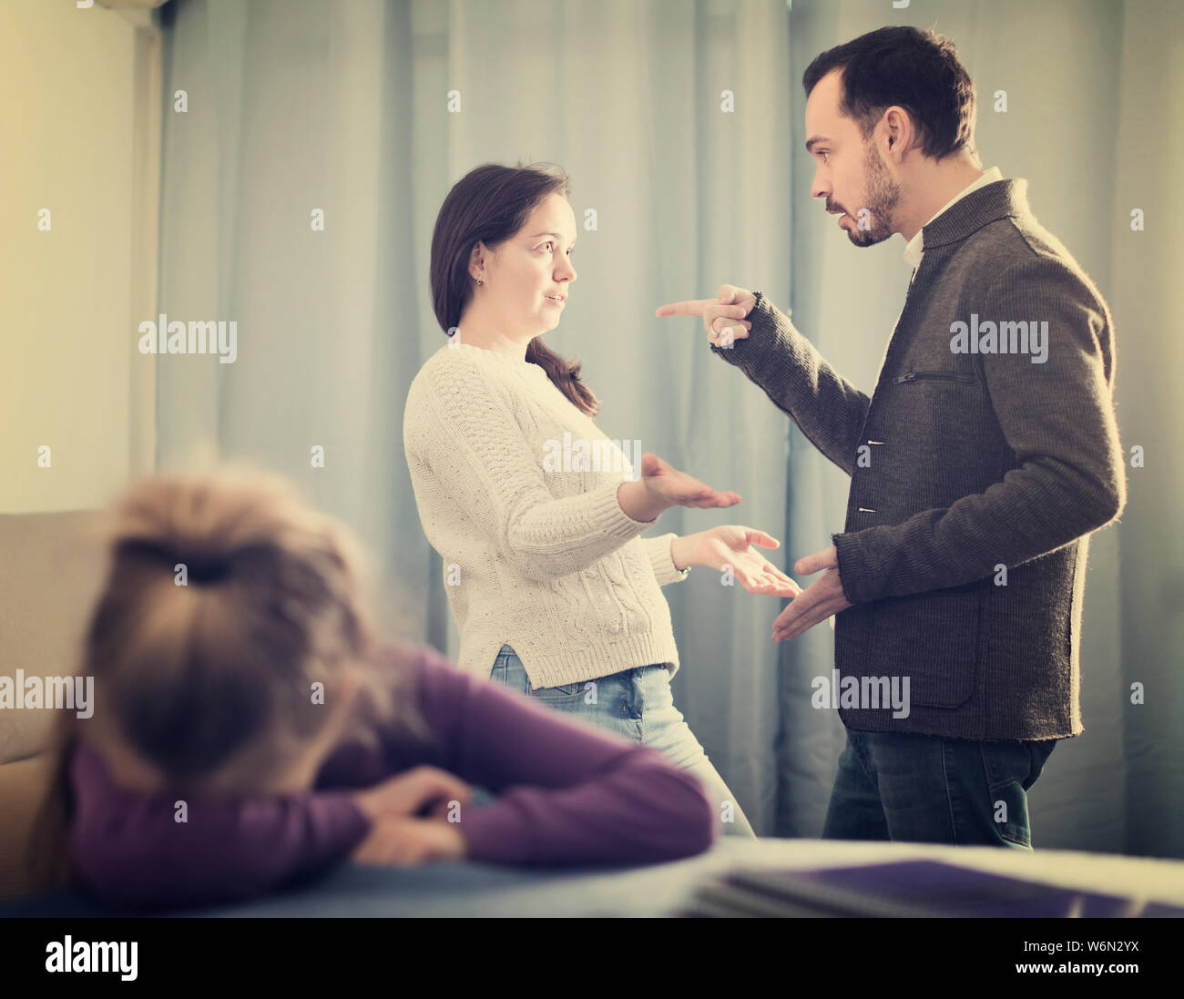 Adult parents arguing with each other while their daughter at home ...