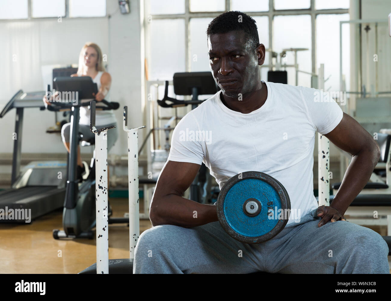 Confident african man doing strength exercises with barbell in gym ...