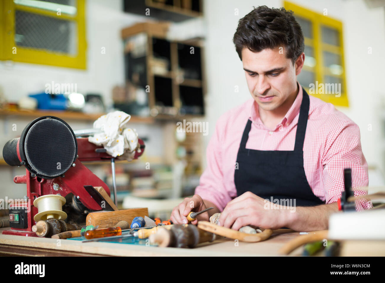 Skilled concentrated joiner working in workshop with chisel in hands ...