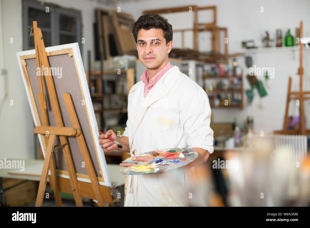 Happy art painter holding artist palette and painting on canvas Stock ...