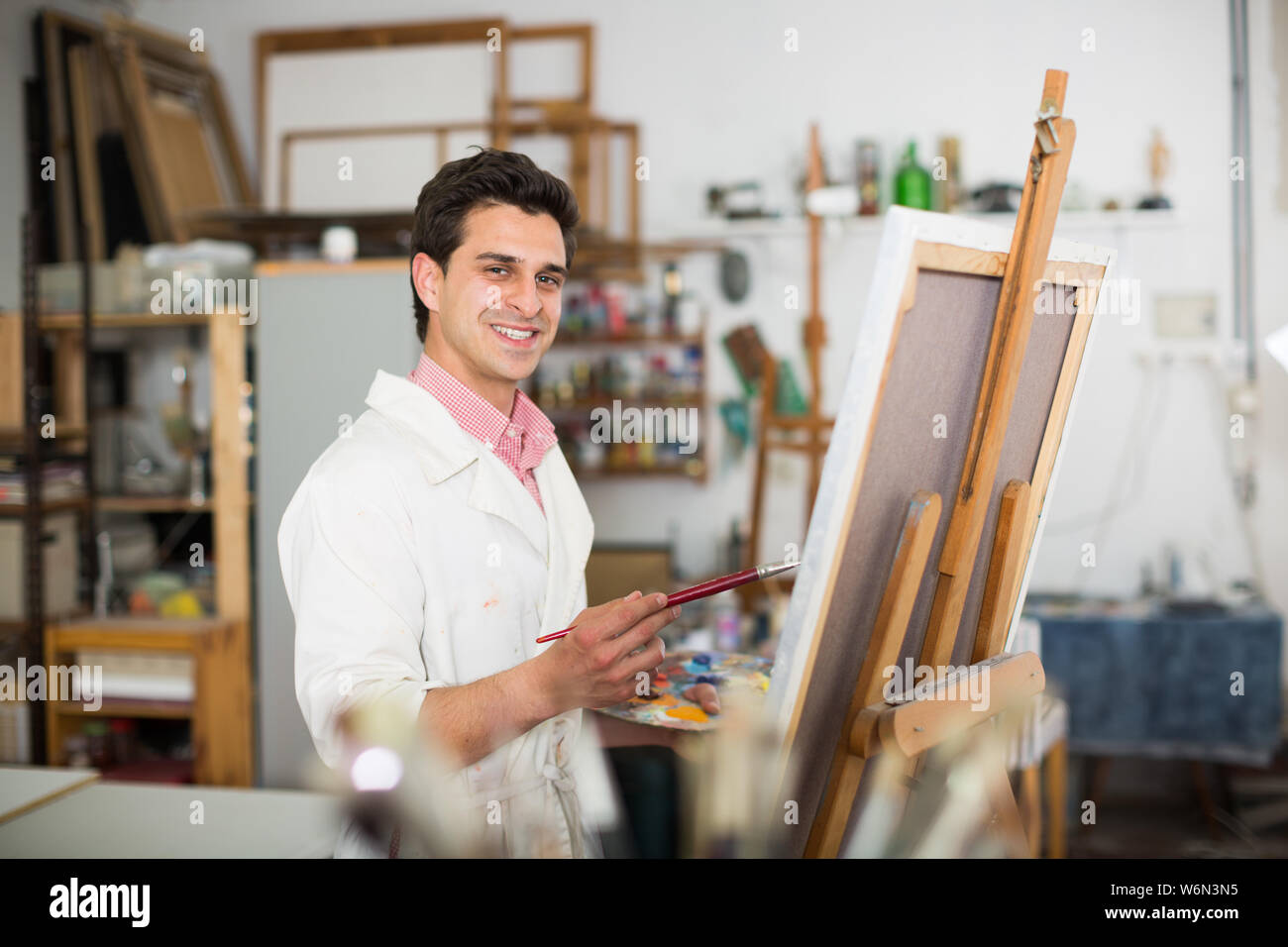 Happy art painter holding artist palette and painting on canvas Stock ...
