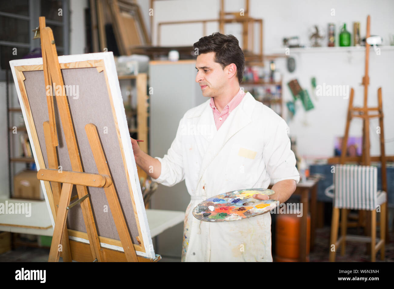 Happy art painter holding artist palette and painting on canvas Stock ...