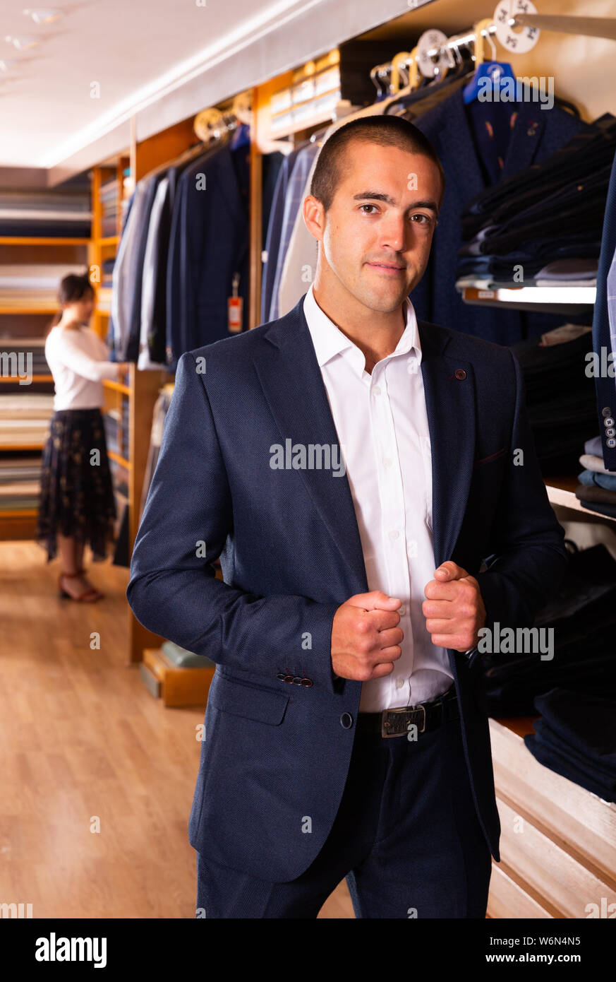 Positive male customer choosing fashion suit in mens store Stock Photo ...