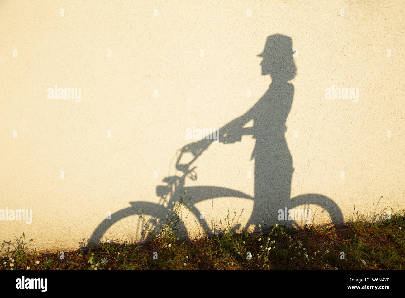 female silhouette with bicycle profile view at yellow concrete wall ...