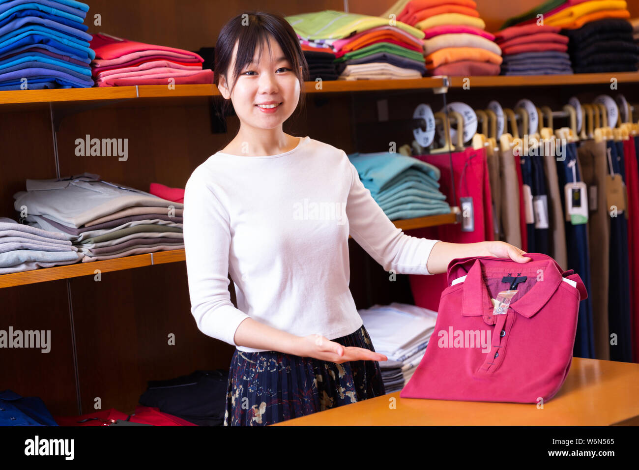 Chinese female shopping assistant offering various shirt in men’s ...