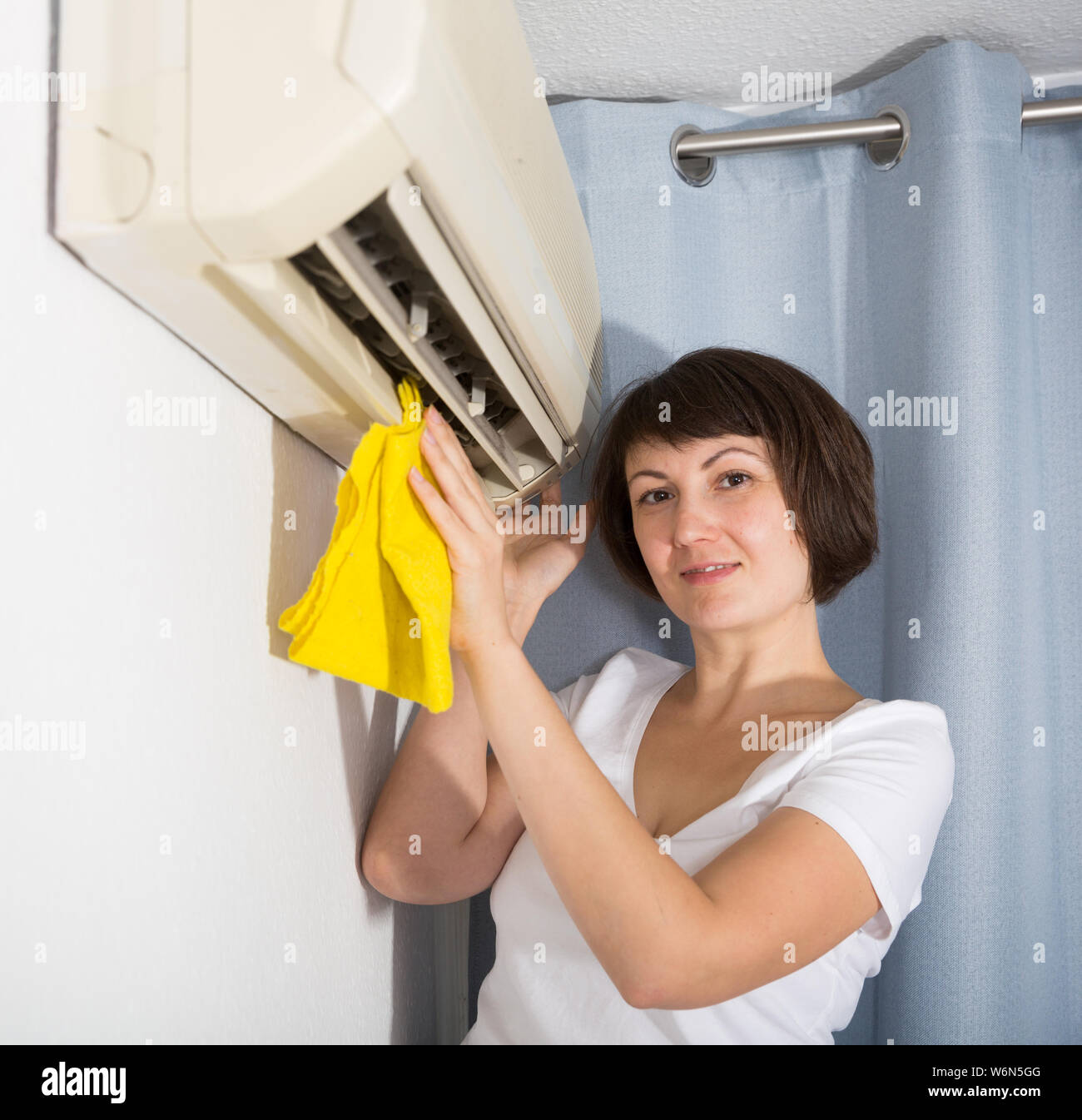 Cheerful woman cleaning with rag air conditioner in her house Stock ...