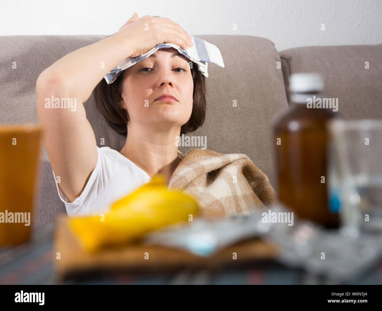 Woman suffering from headaches and fever on sofa at home Stock Photo ...