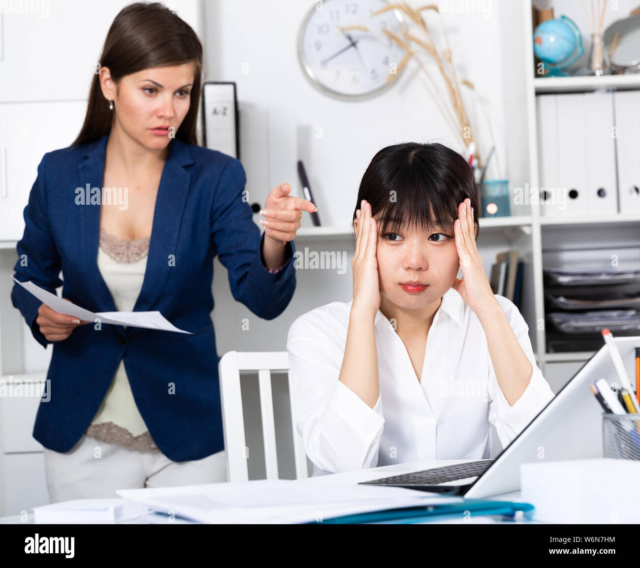 Upset chinese business woman sitting at laptop in office on background ...