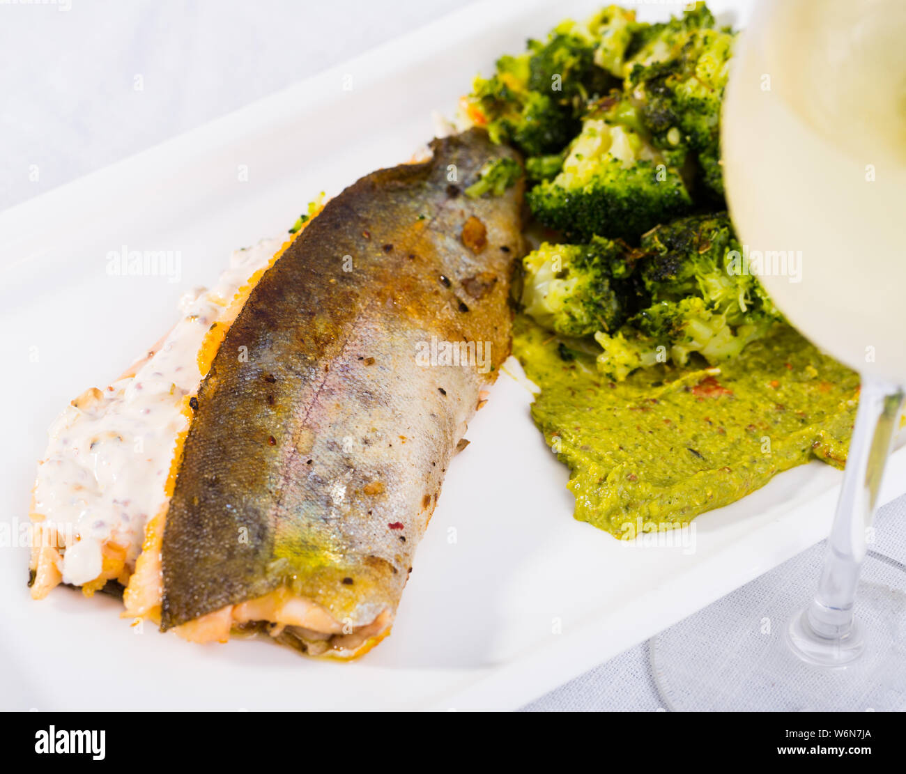 Delicious fried brook trout fillets with broccoli served with glass of ...