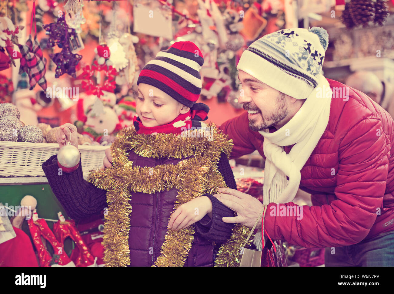 Positive male with small daughter choosing decorations for Xmas in Christmas market Stock Photo ...