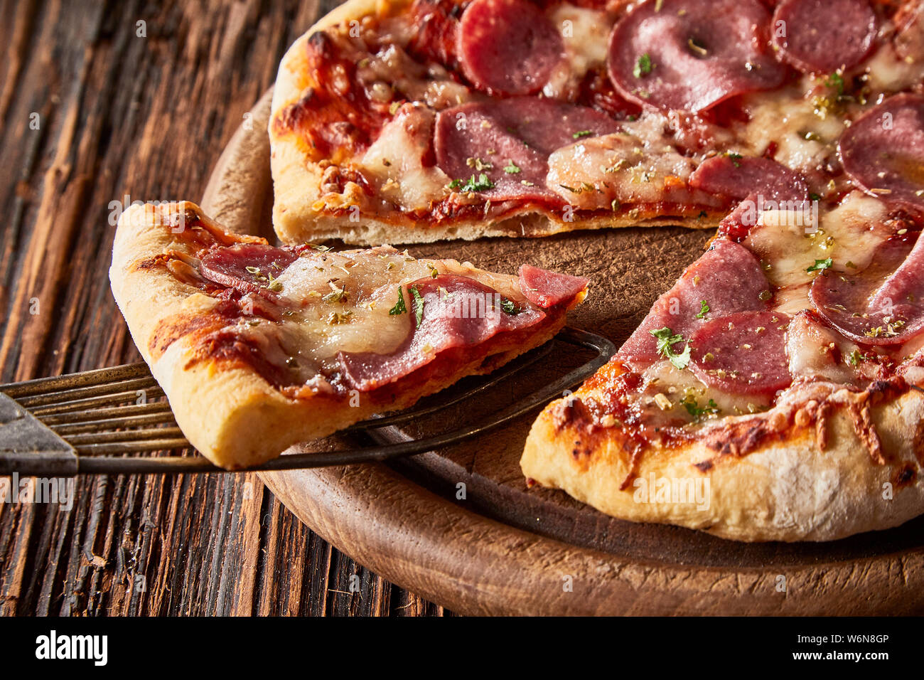 Slice of Italian pepperoni pizza on a spatula with a wedge cut from the ...