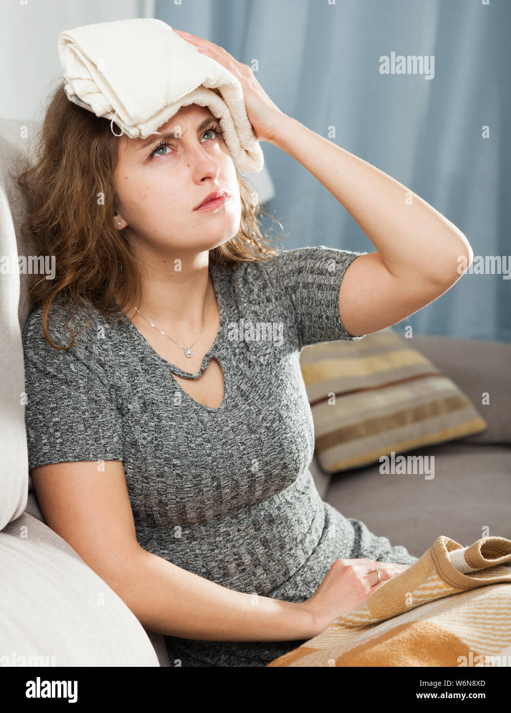Woman with wet towel on her forehead suffering from headaches at home ...