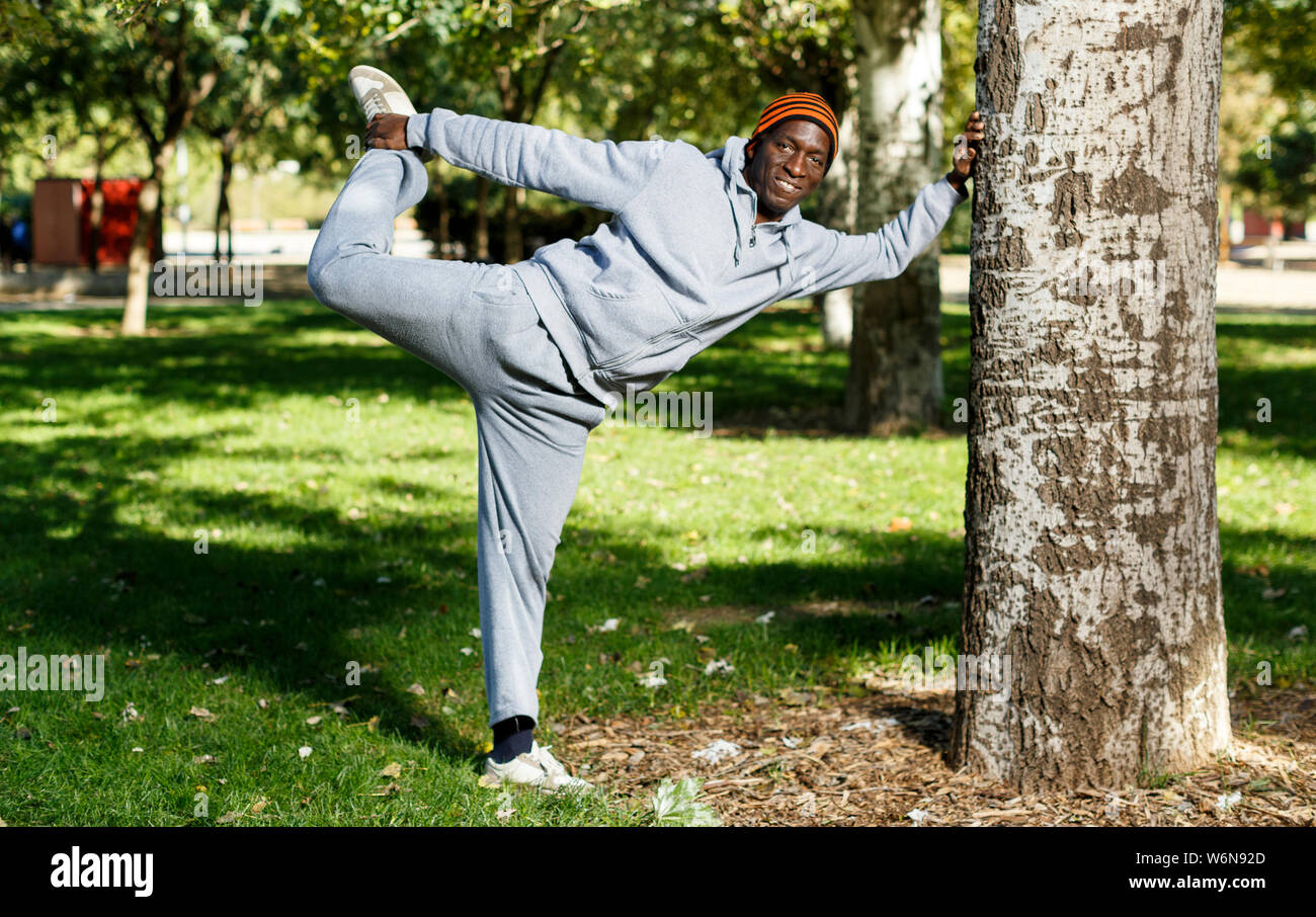 Active young male training different exercises near tree at park ...