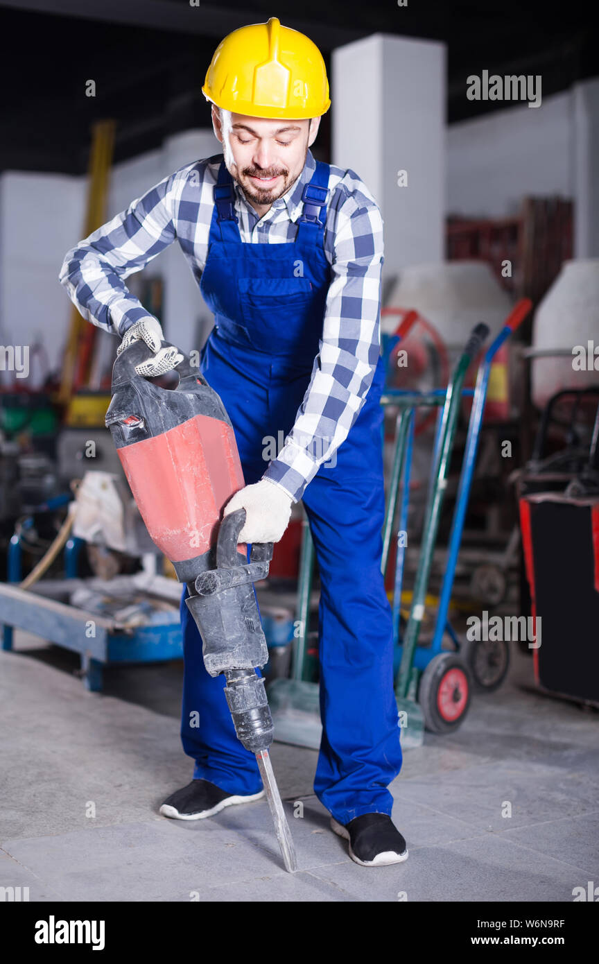 positive working man practicing his skills with pneumatic drill at ...