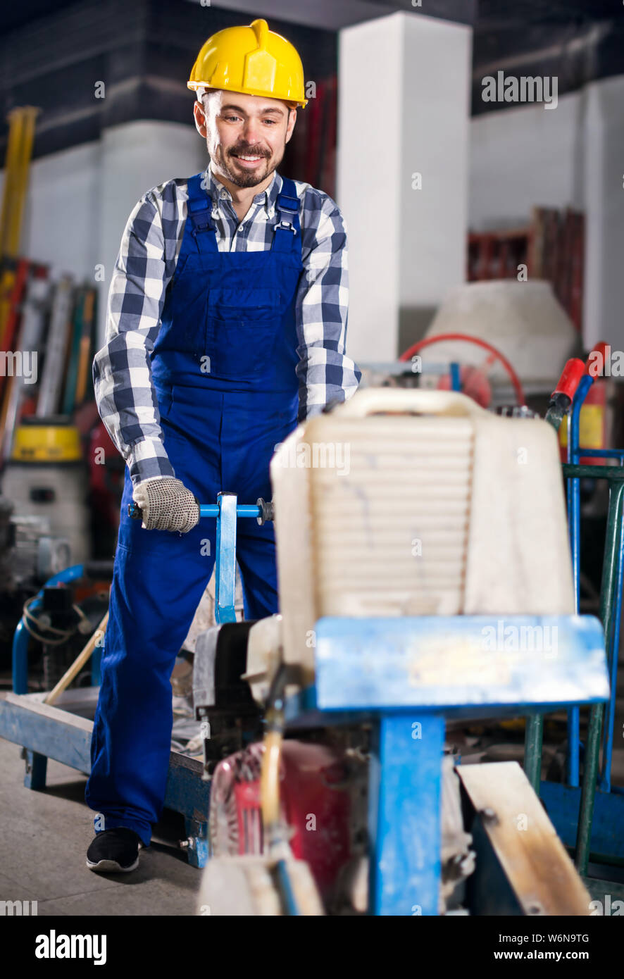 Smiling working man practicing his skills with edger at the workshop ...