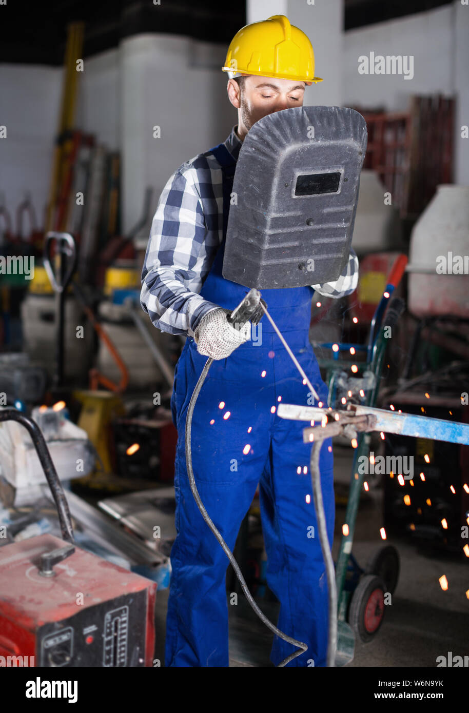 Smiling working male practicing his skills with welding set at ...