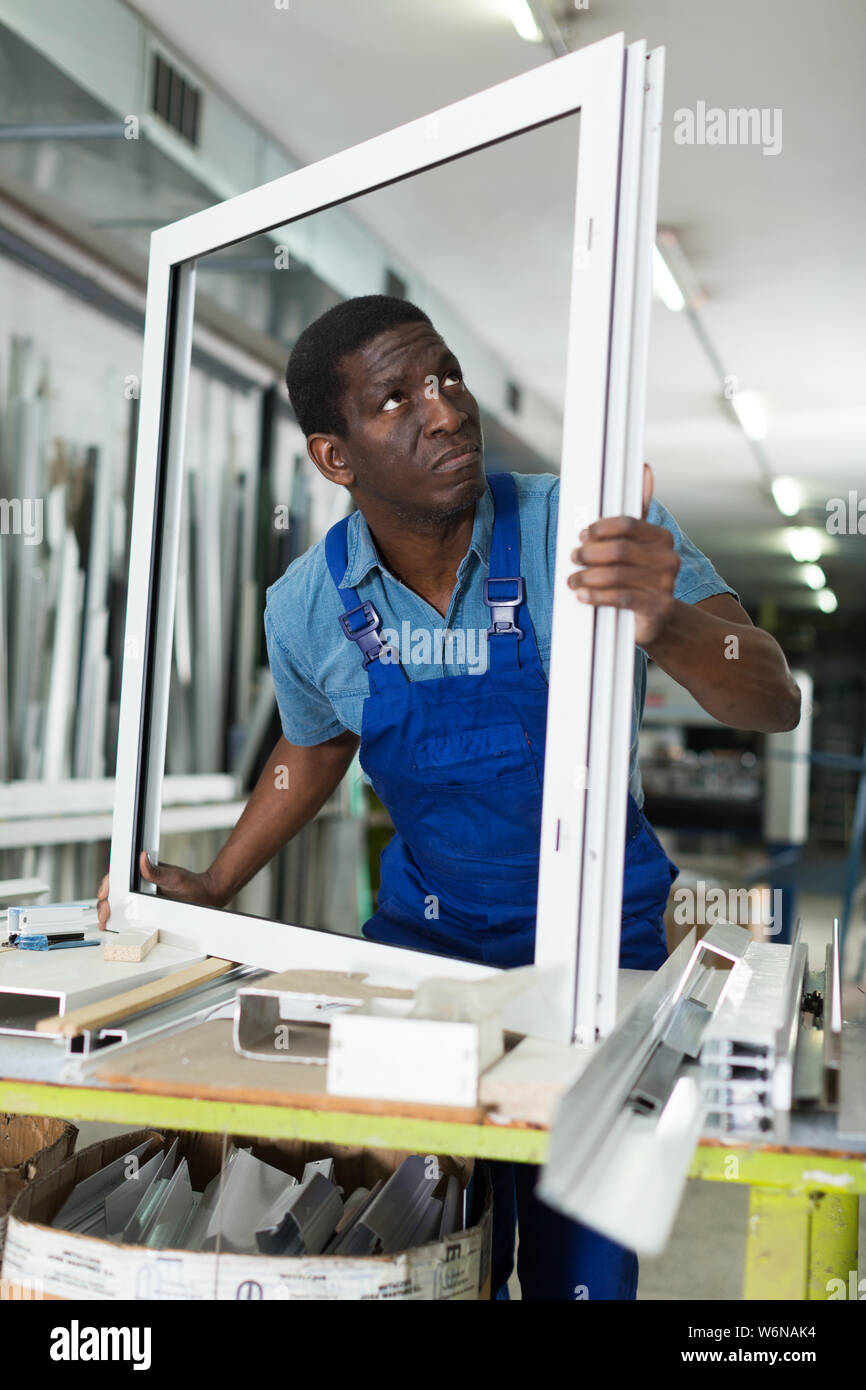 Portrait of man worker who is standing with window frame in the pvc ...