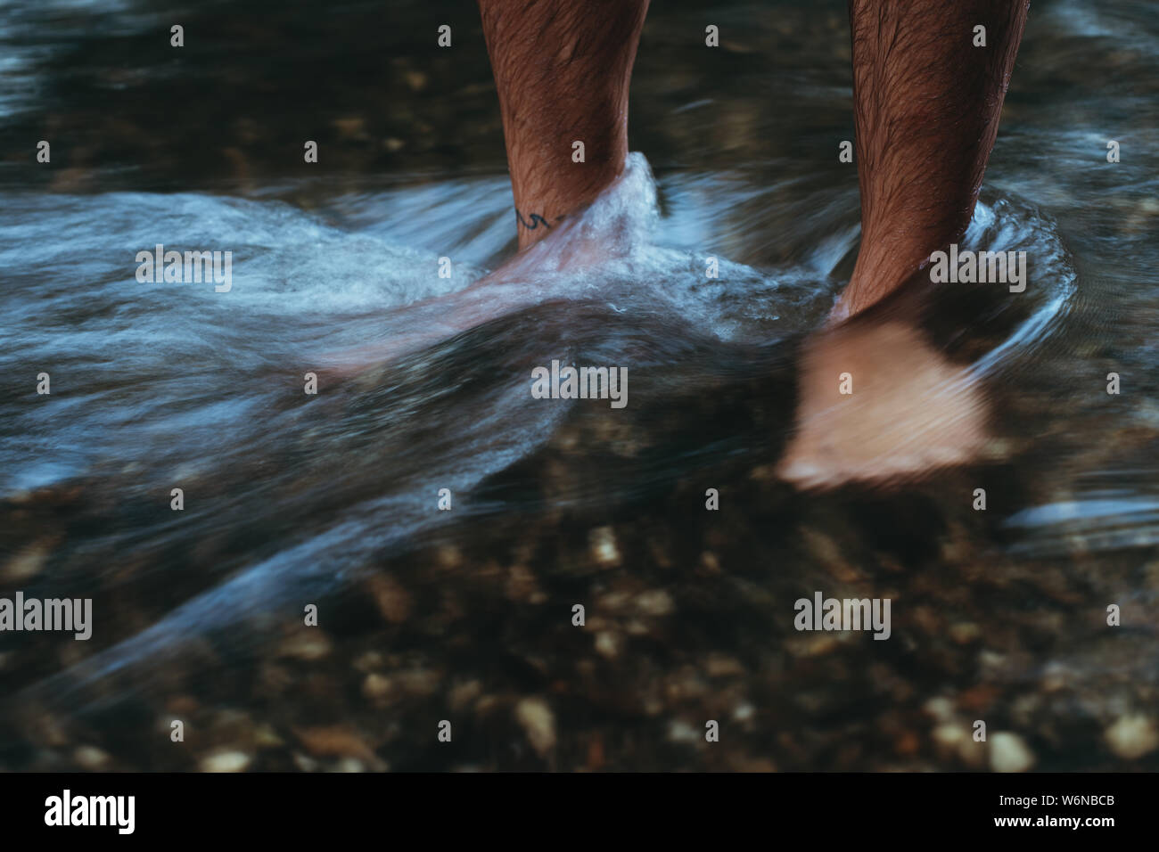 flowing water around the ankles of a human feet standing in a river ...