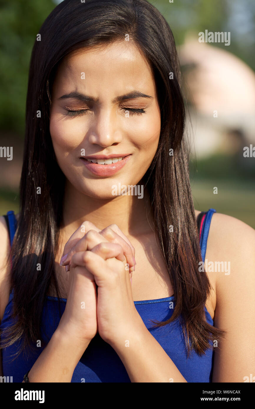 Woman wishing with clasped hands Stock Photo - Alamy
