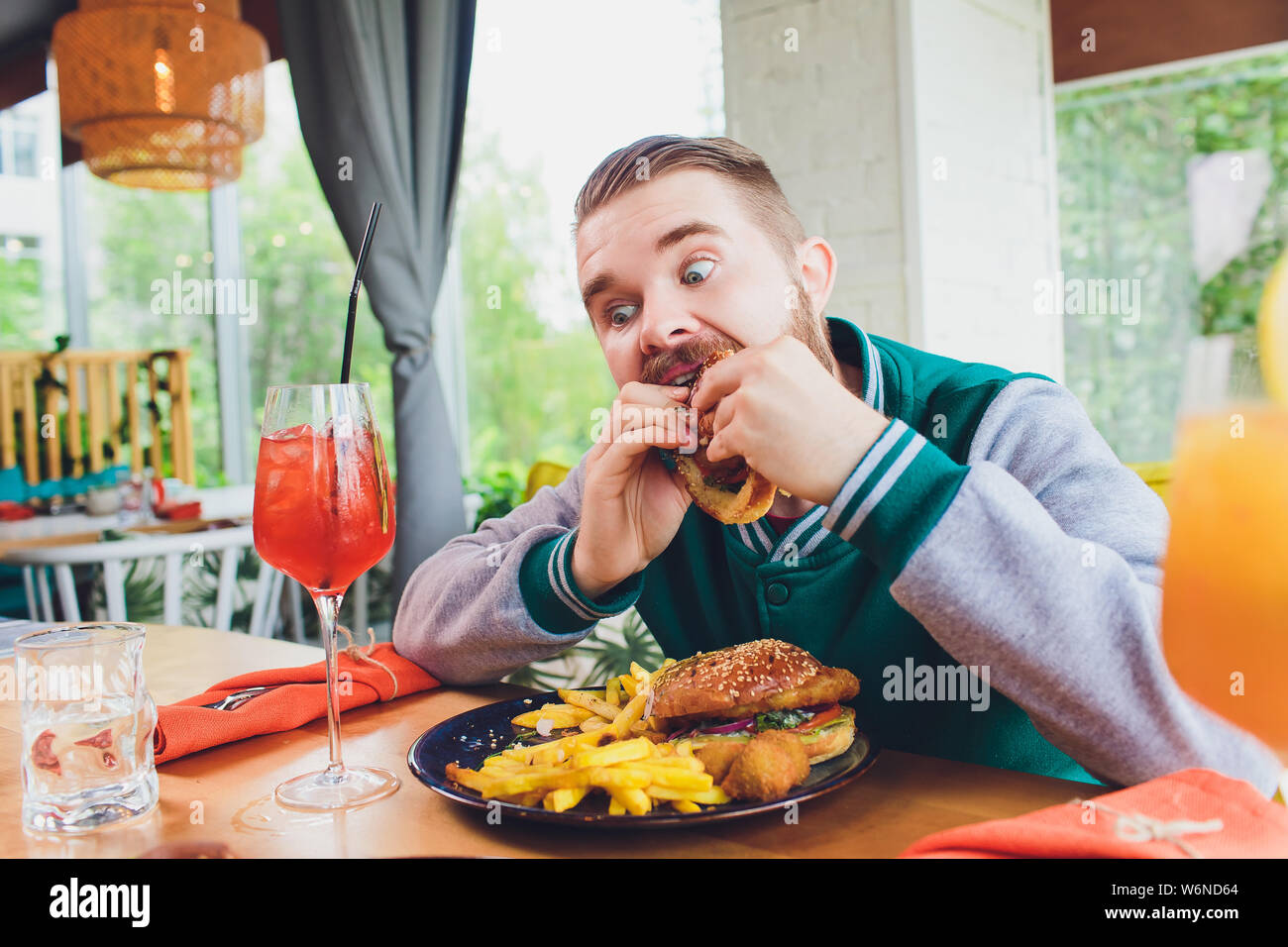 Picture of happy man eating vegan burger in vegan restaurant or cafe ...