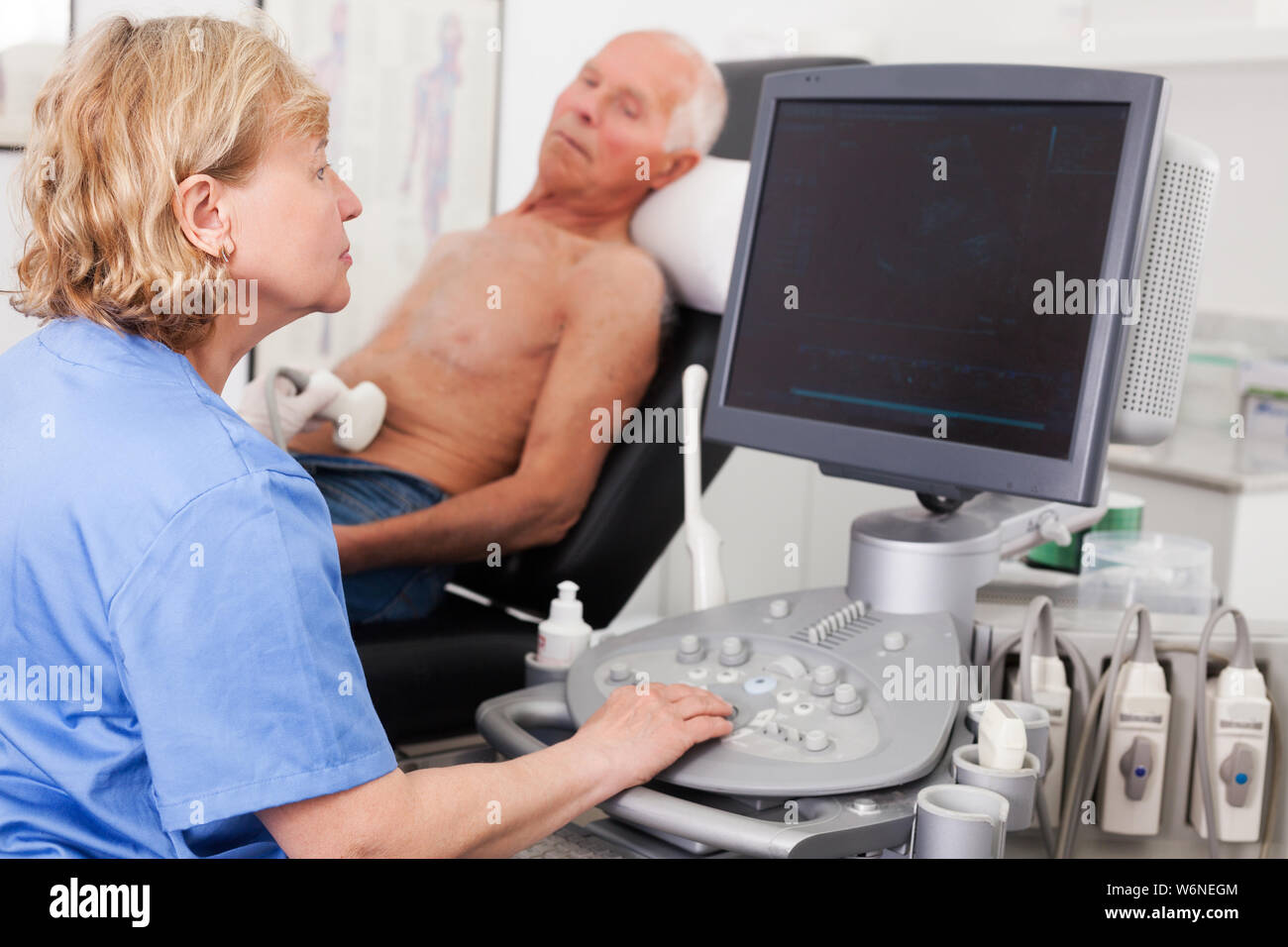 Hospital serious woman doctor examines a senior man with ultrasonic ...