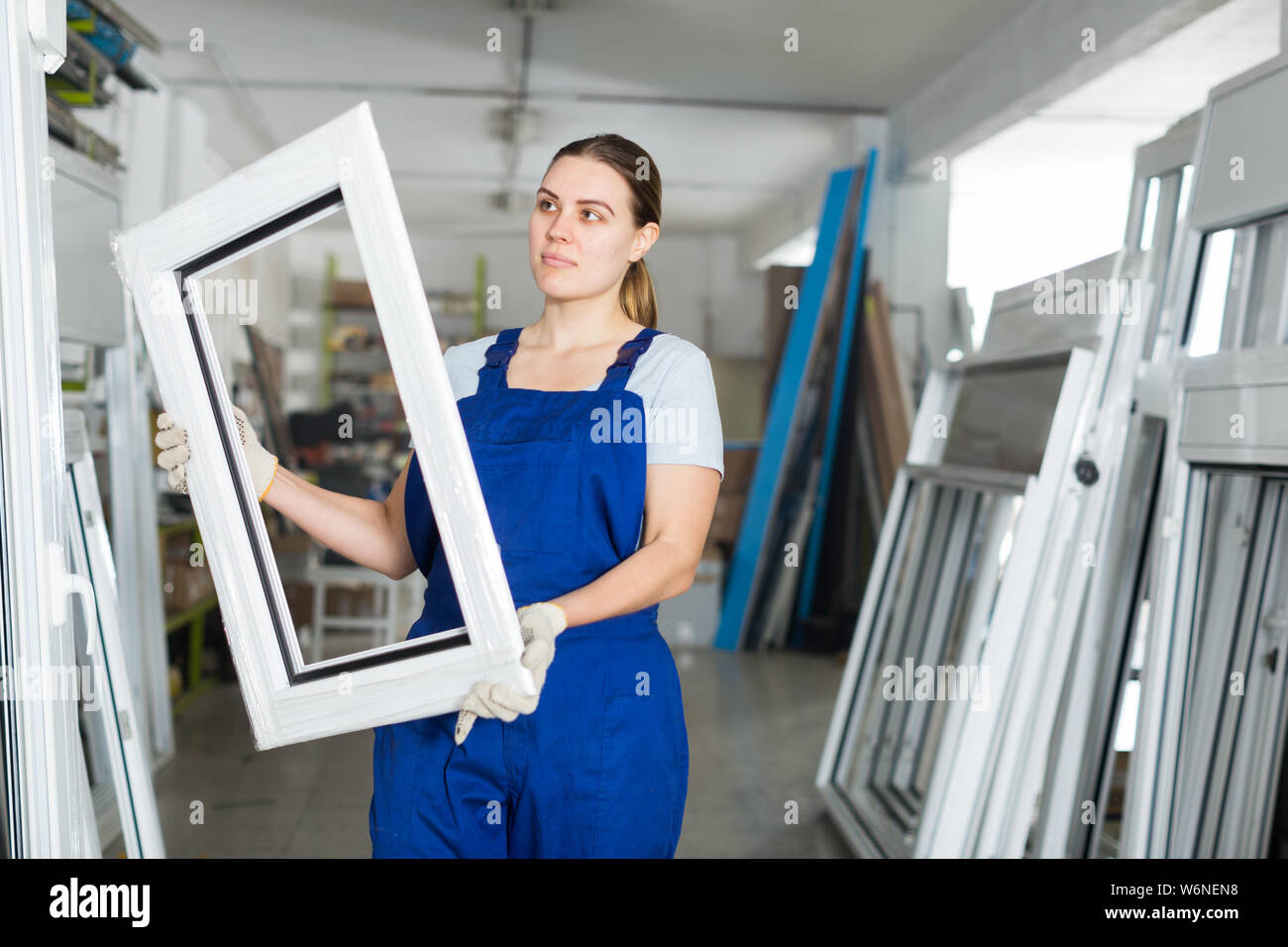 Female master is working with window frame in the window workshop Stock ...