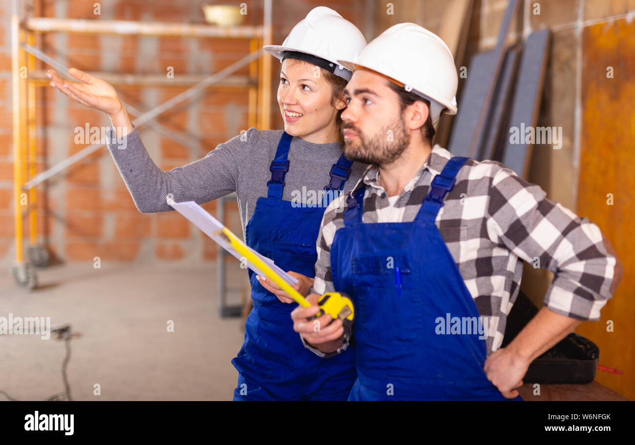 Workers man and woman discuss construction plan Stock Photo - Alamy
