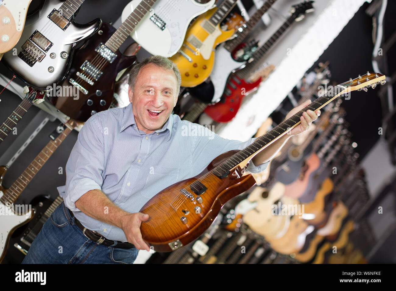 Smiling man demonstrating an electric guitar in a music store Stock ...