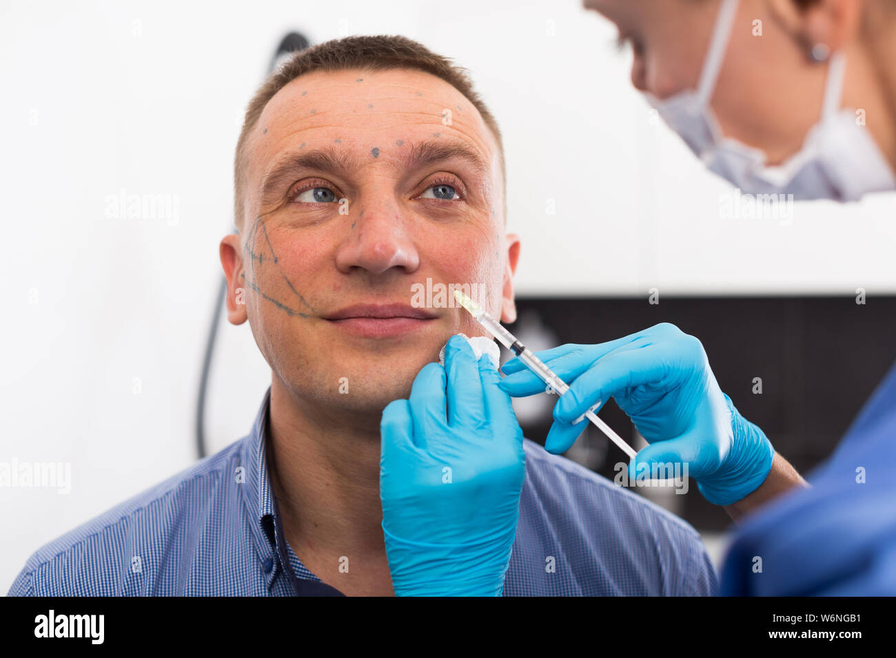 Female doctor is doing injection to patient in skin of face in estetic ...