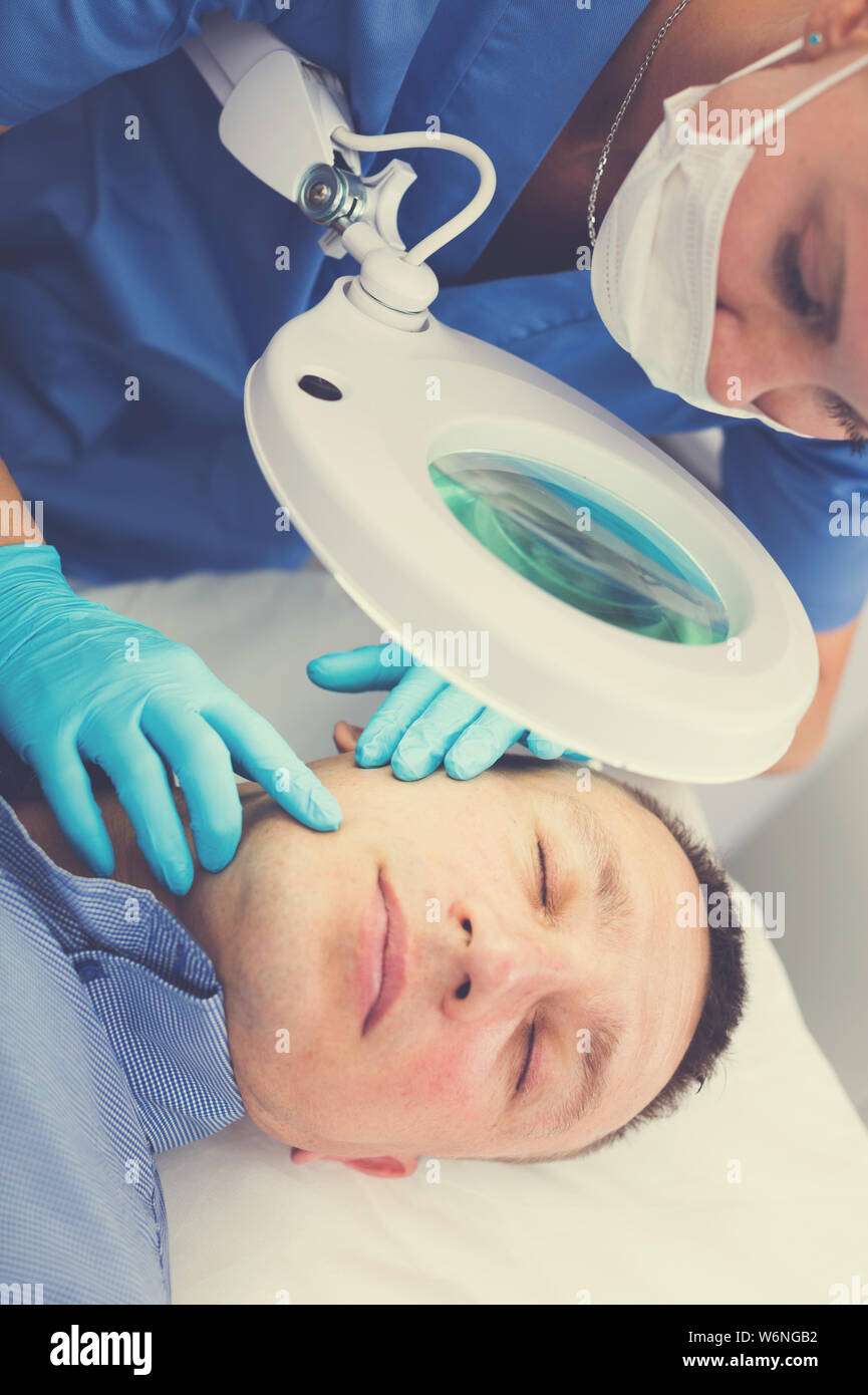 Female doctor is doing cleaning skin procedure to client in cabinet ...