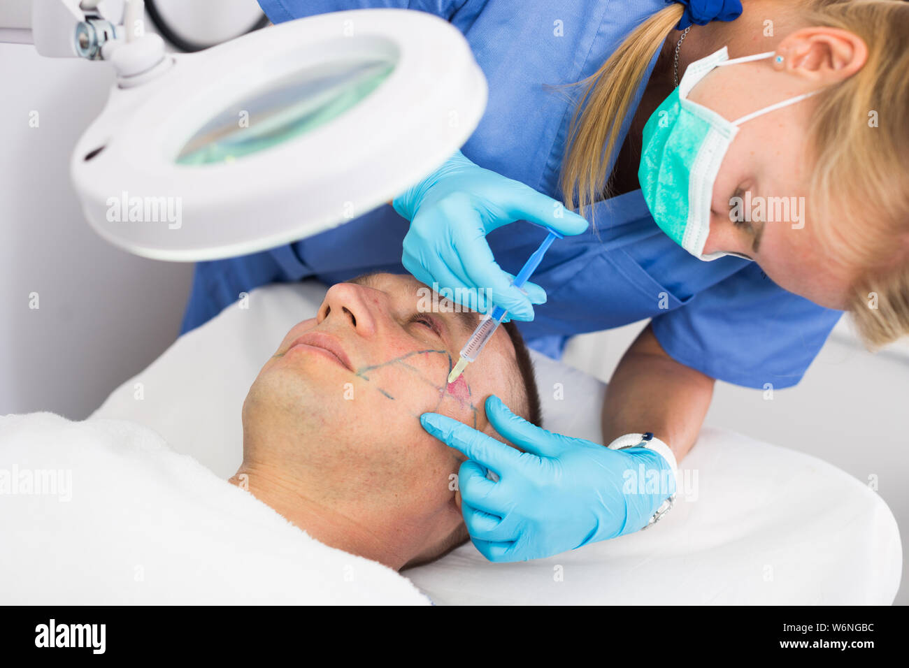 Female doctor is doing injection to patient in skin of face in estetic ...