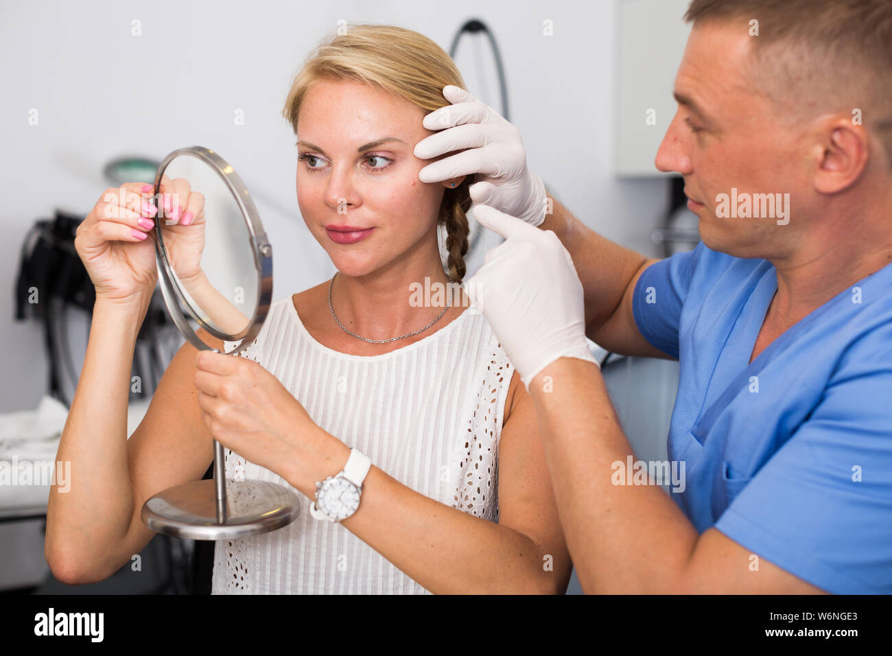 Doctor is examining woman patient behind mirror before the procedure in ...