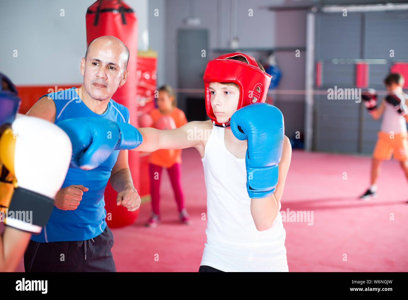 Boxing instructor controls the sparring between the two boys in the gym ...