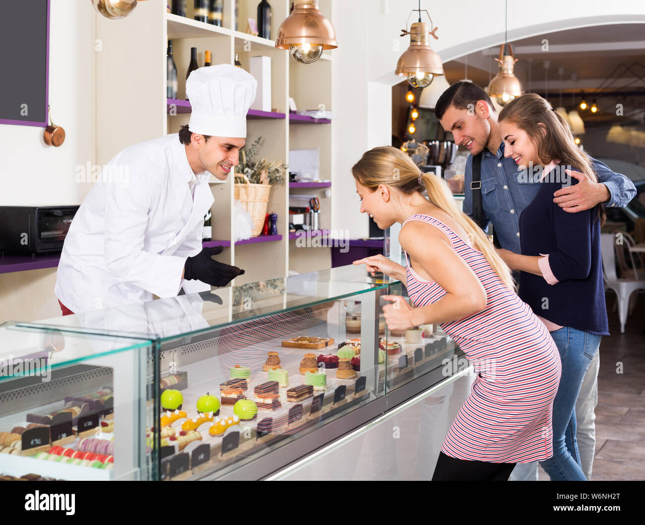 Positive pastry chef man is serving visitors in cozy pastry shop Stock ...
