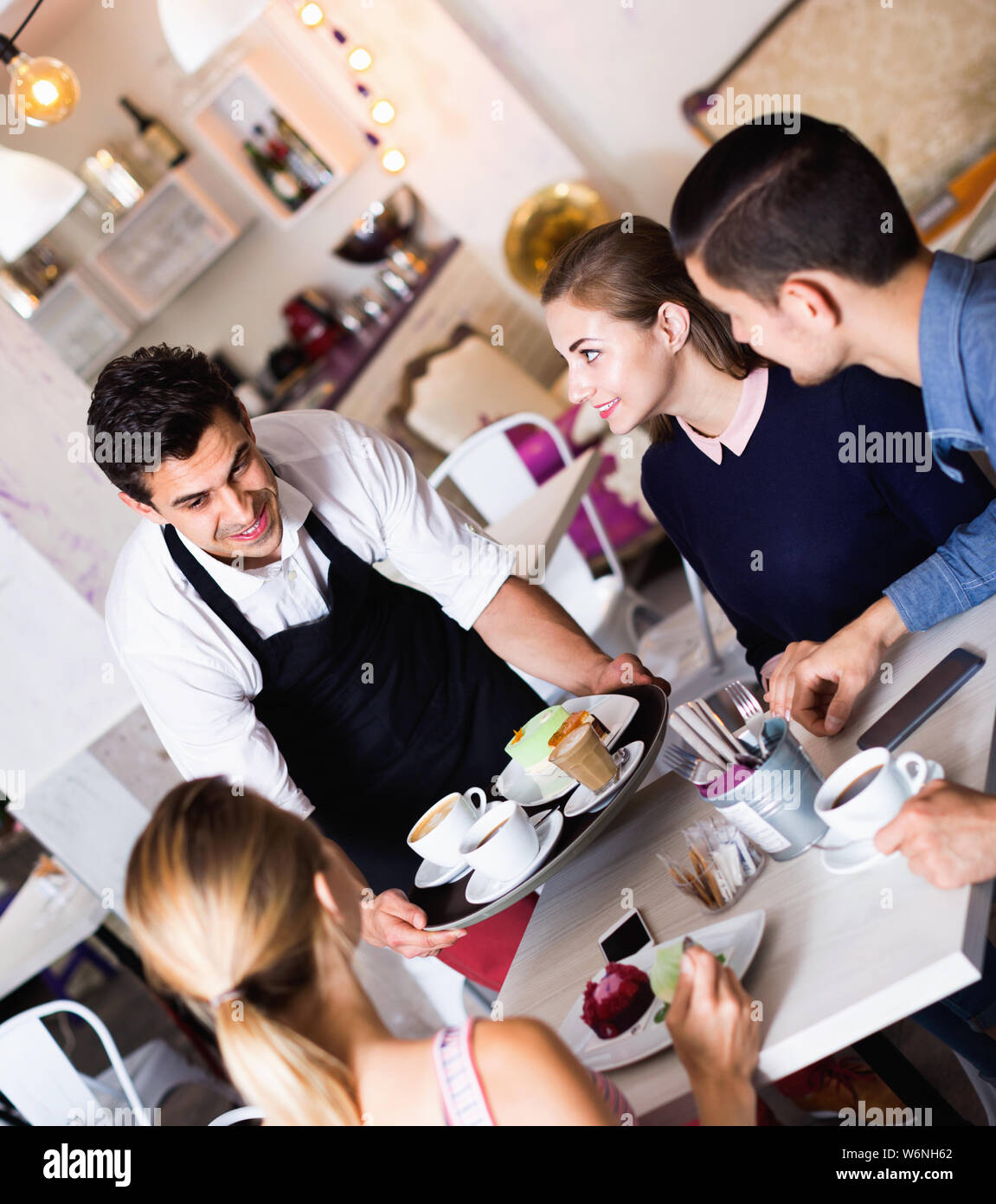 Pleasant smiling waiter showing hospitality and serving visitors in ...
