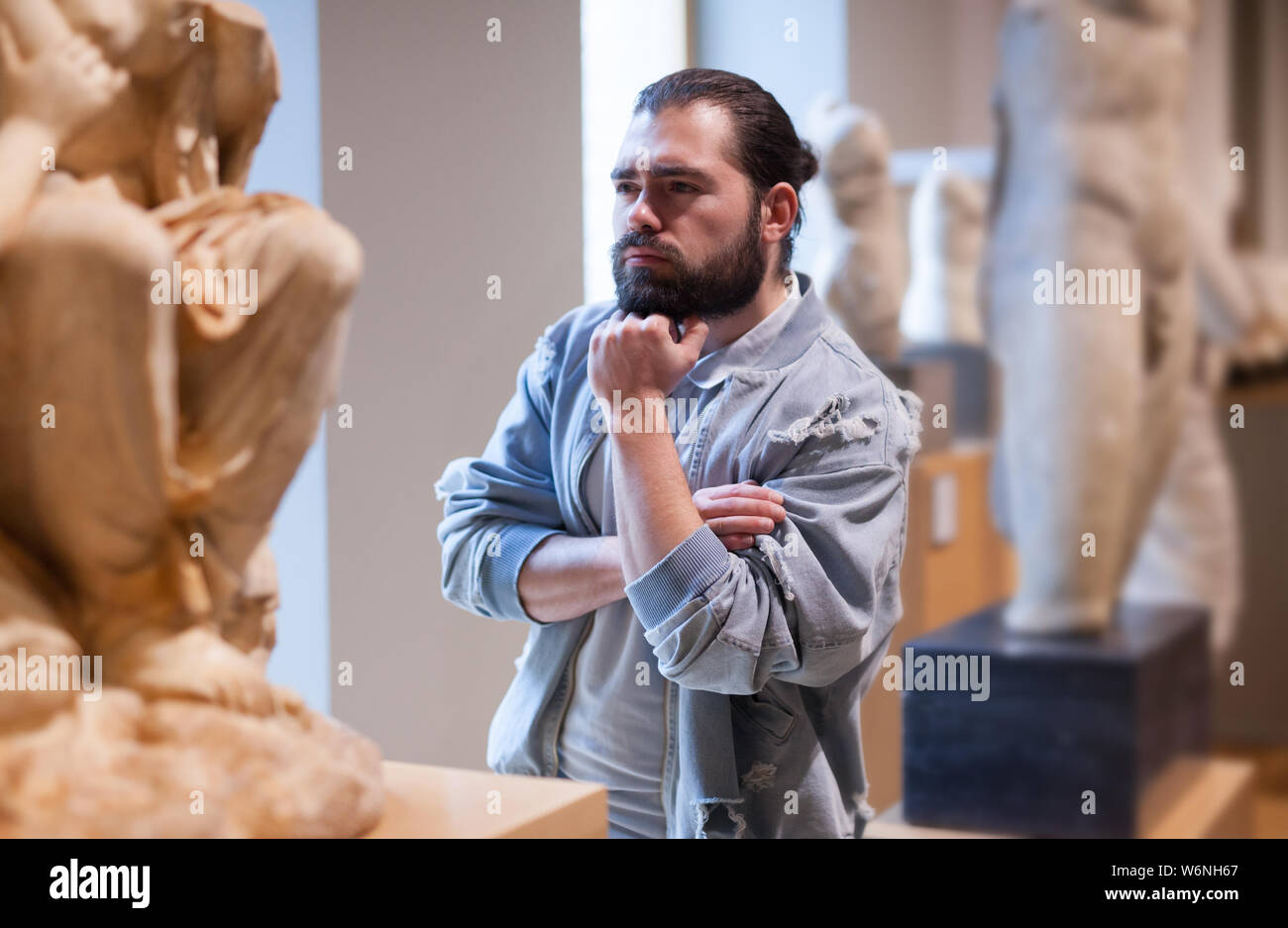 Man looking at stone architectural elements in historical museum hall ...