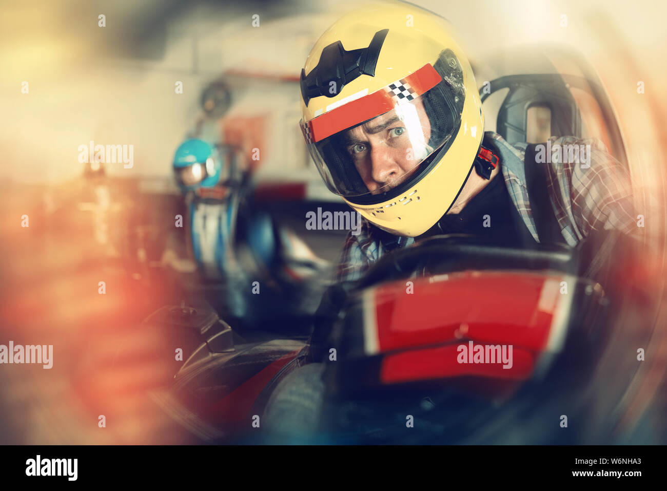 active young man and his friends competing on racing cars at kart ...