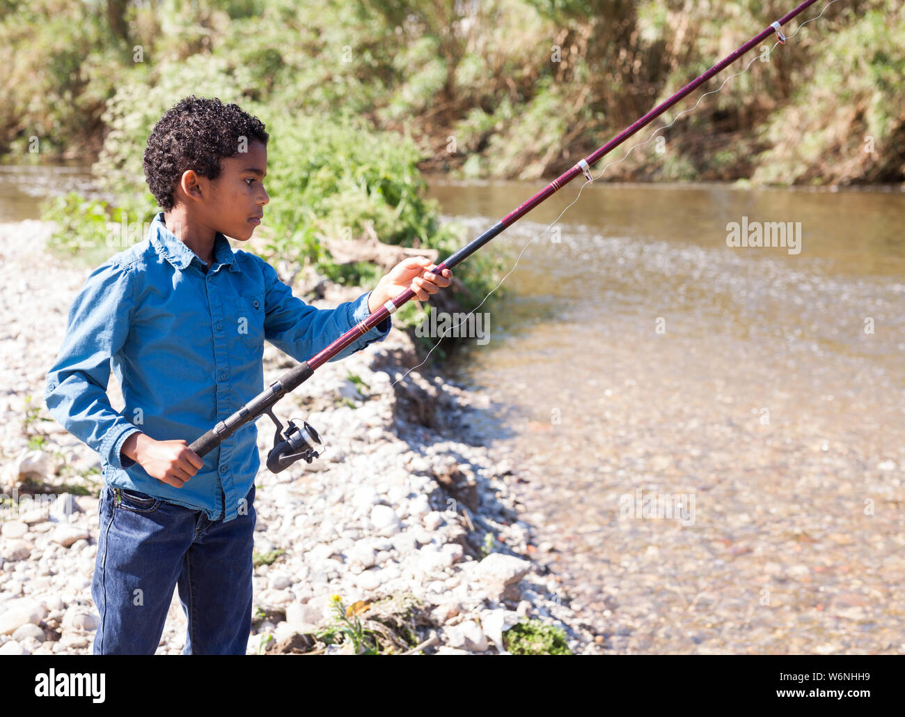 Portrait of little Afro-American boy fishing with rod on river Stock ...