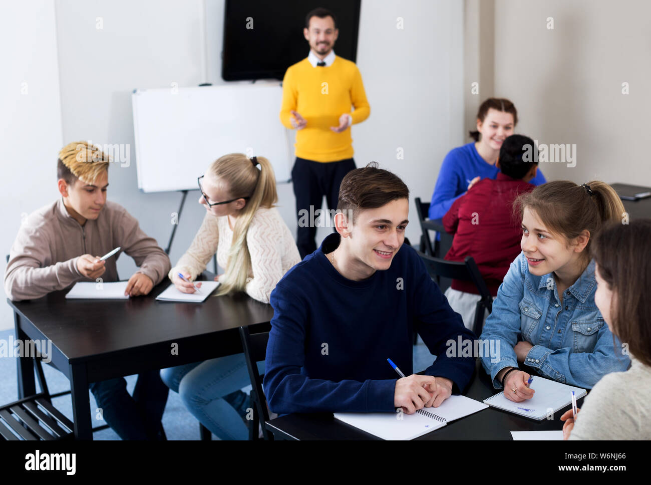 Happy classmates and teacher working in groups to complete task during ...