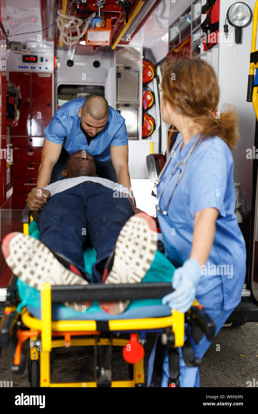 Emergency doctors fixing patient on stretcher in ambulance car Stock ...