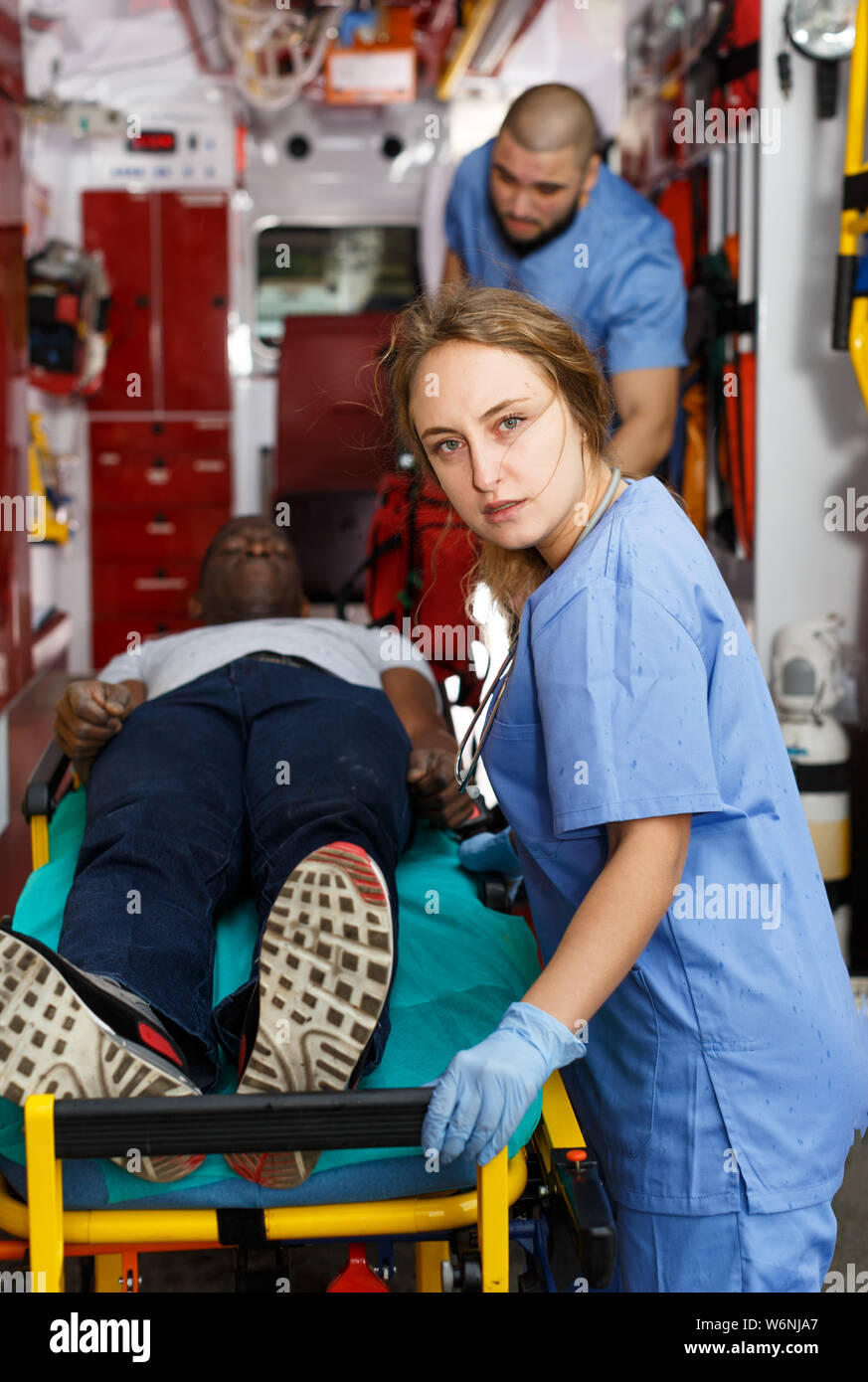 Emergency doctors fixing patient on stretcher in ambulance car Stock ...