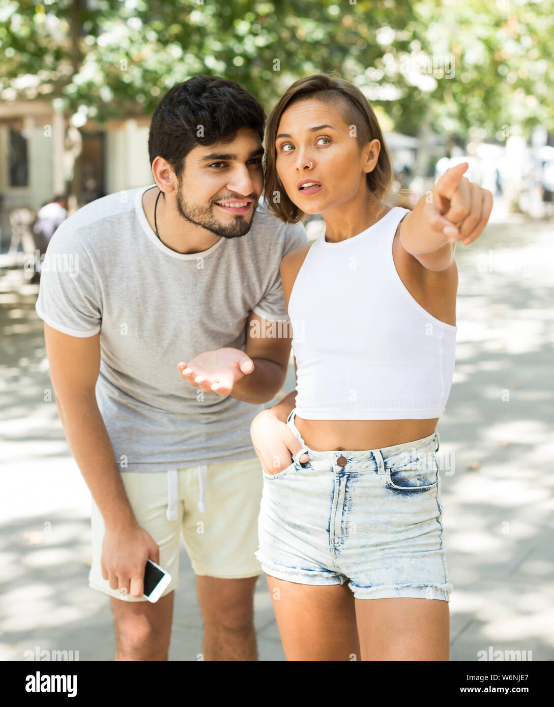 two people talking and pointing finger at the street Stock Photo - Alamy