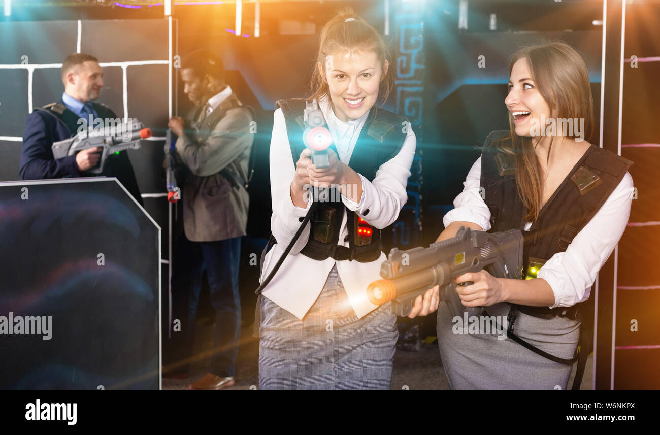 Emotional portrait of two glad women holding laser pistols and playing ...
