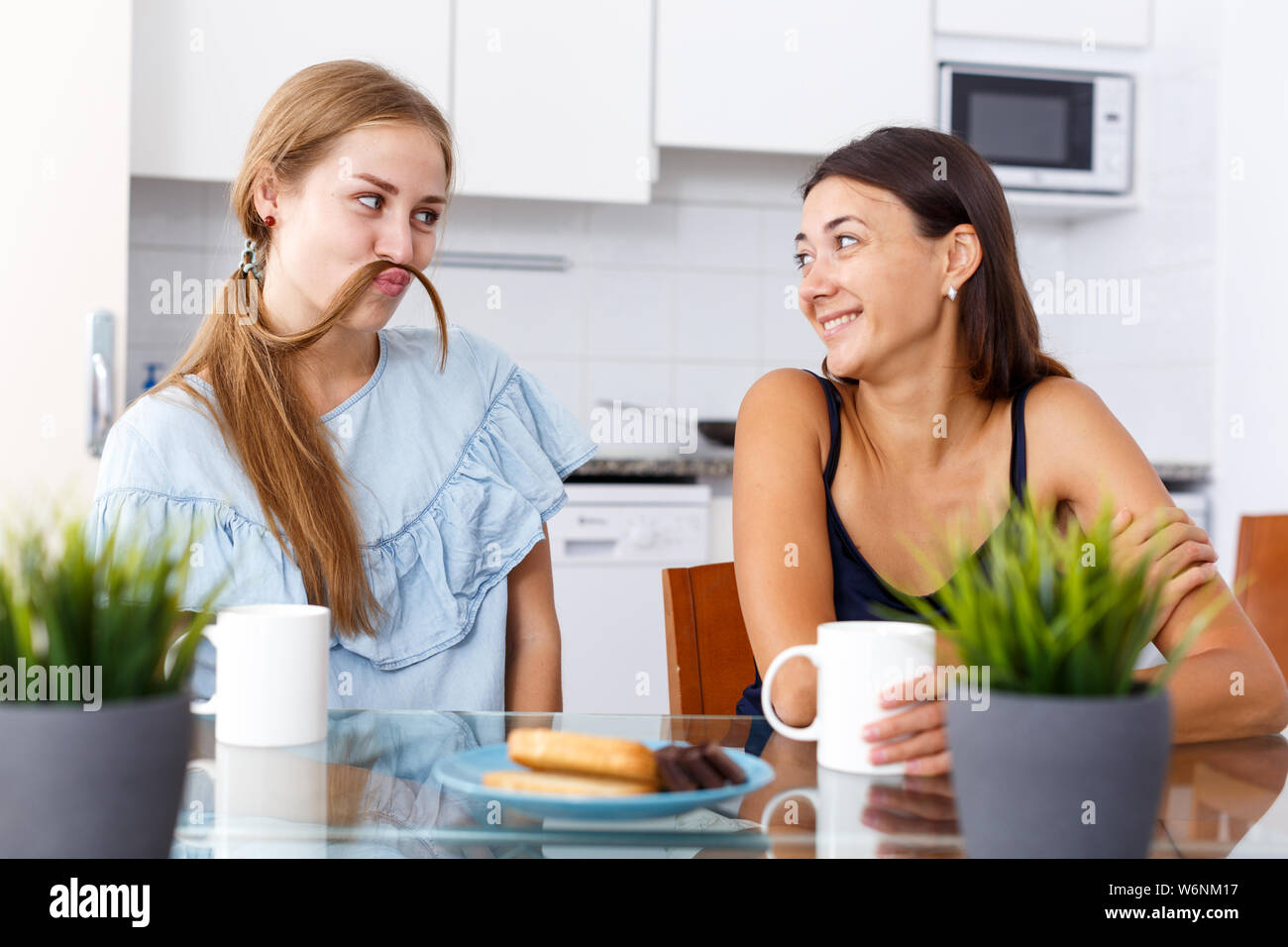 Young smiling emotional girlfriends having fun and drinking tea at ...