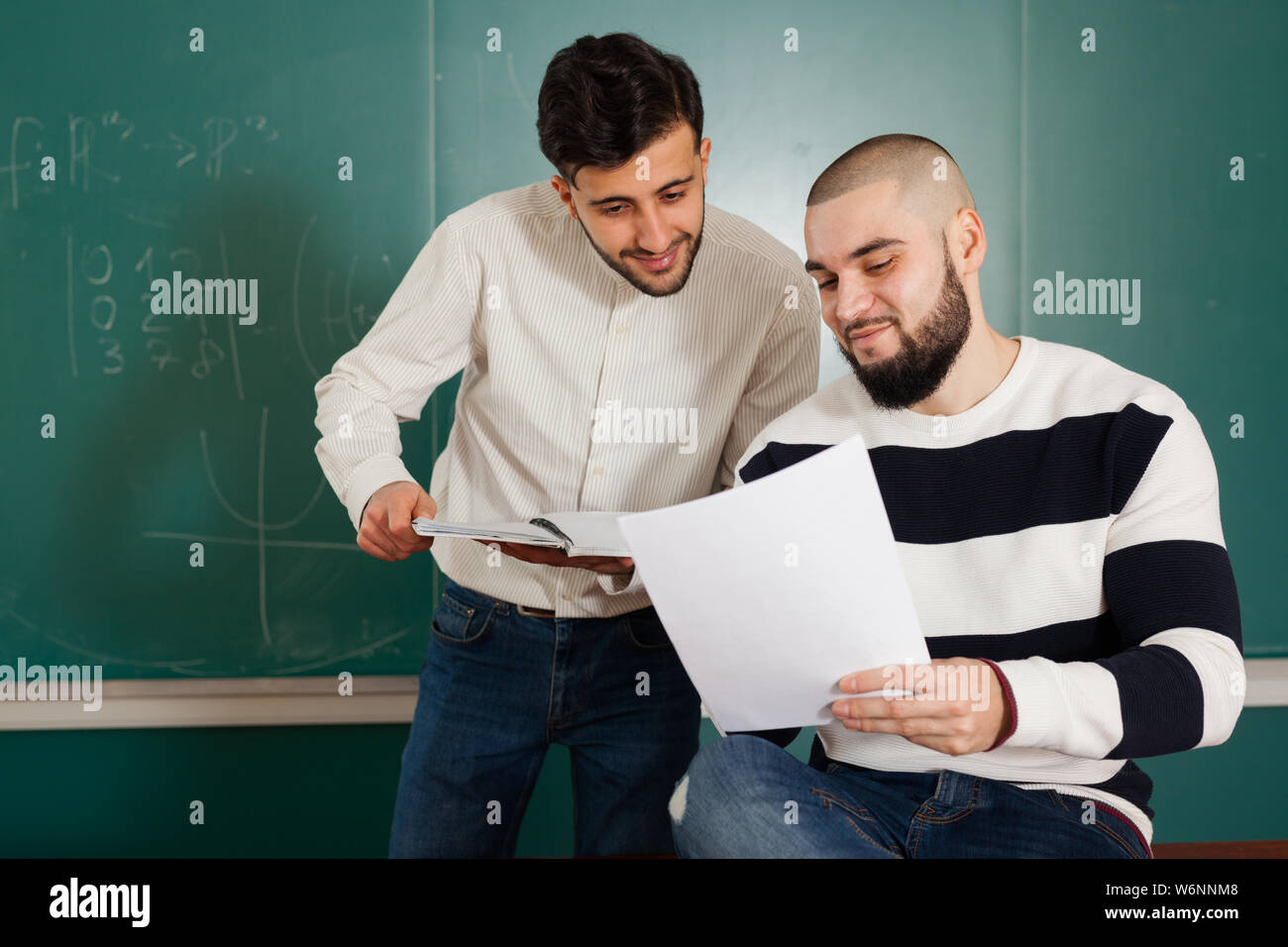 Portrait of two young guys discussing their student project at desk in ...