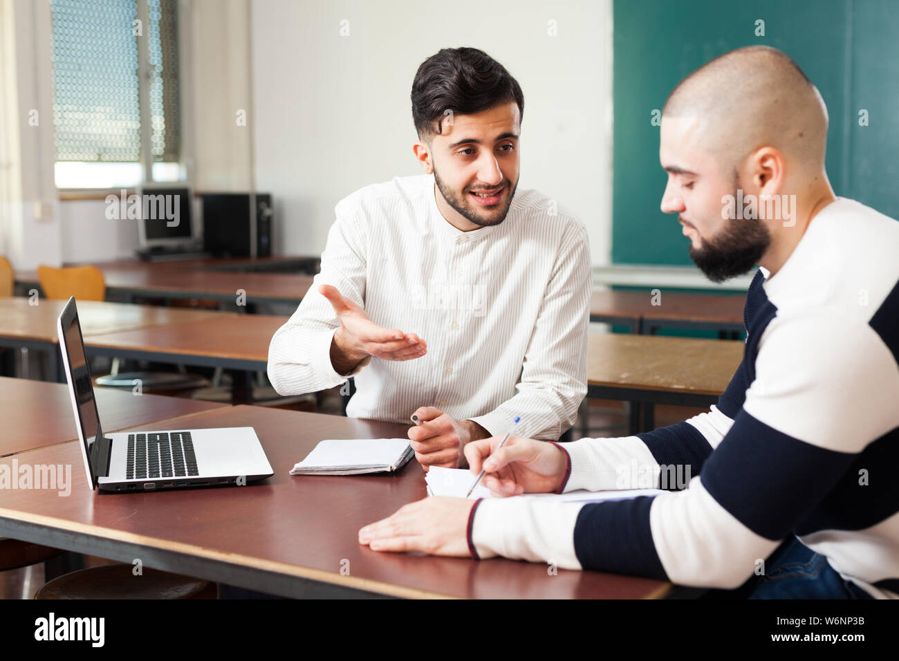 Portrait of two young guys working on their student project at desk in ...