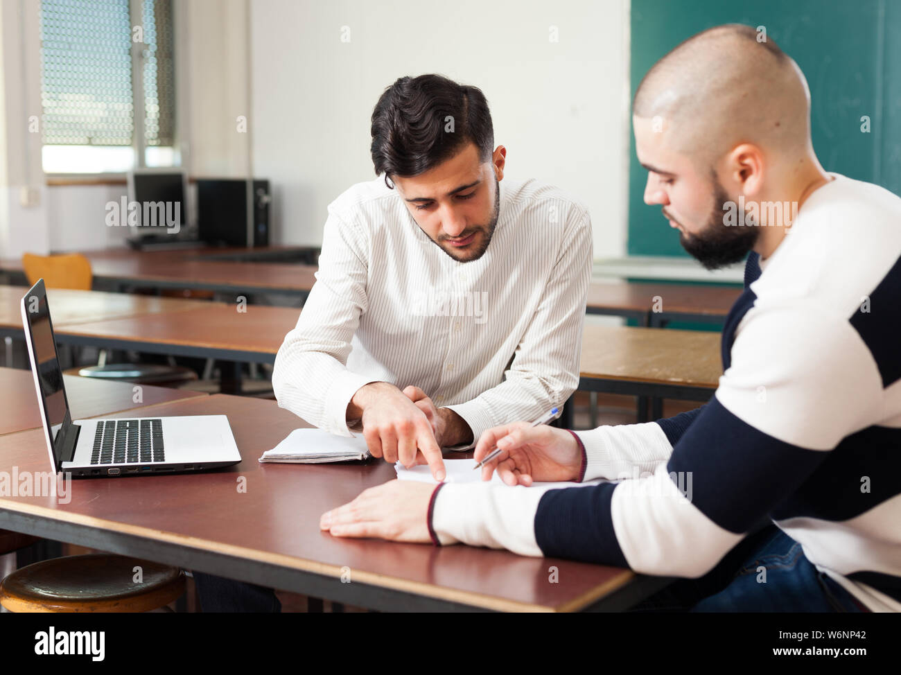 Portrait of two young guys working on their student project at desk in ...
