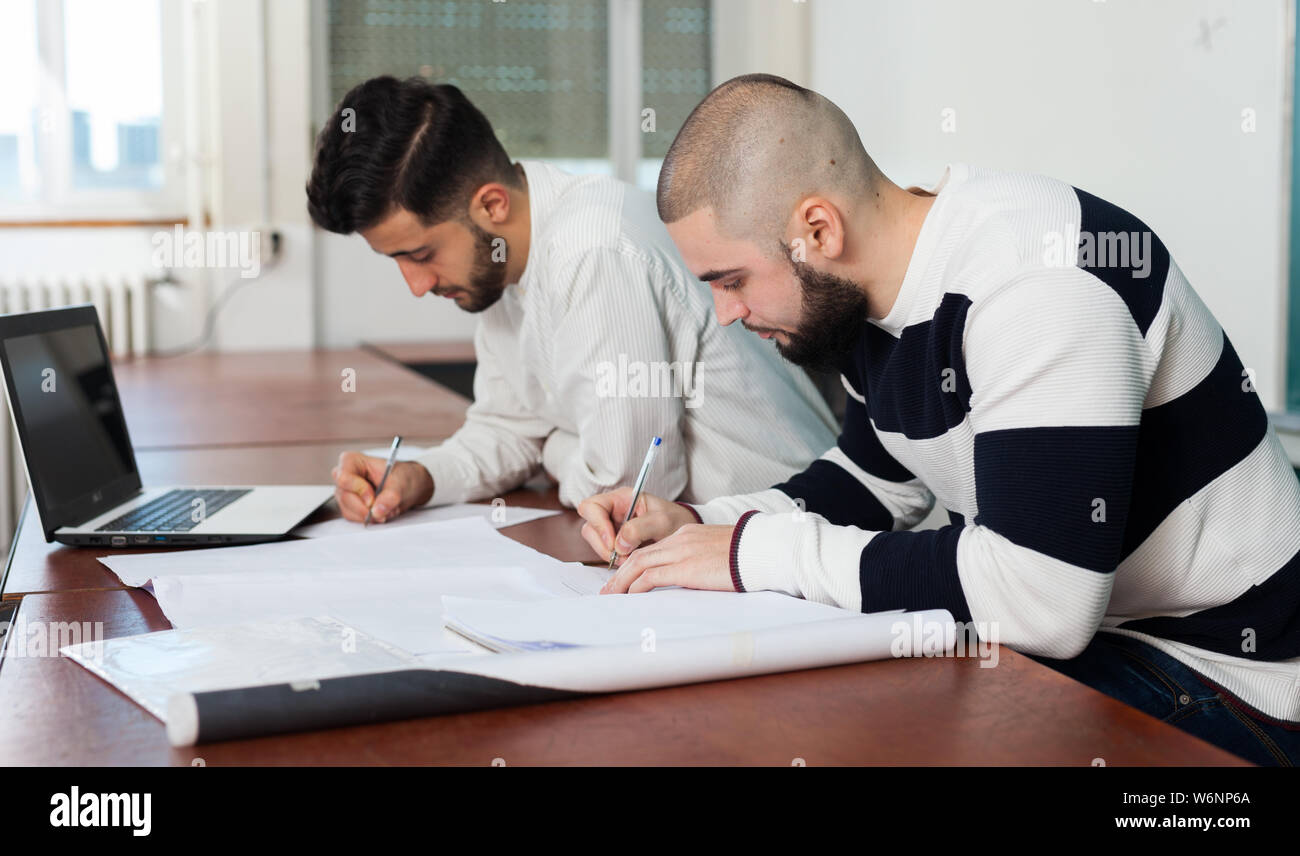 Two male university students sitting at desk preparing for exams ...