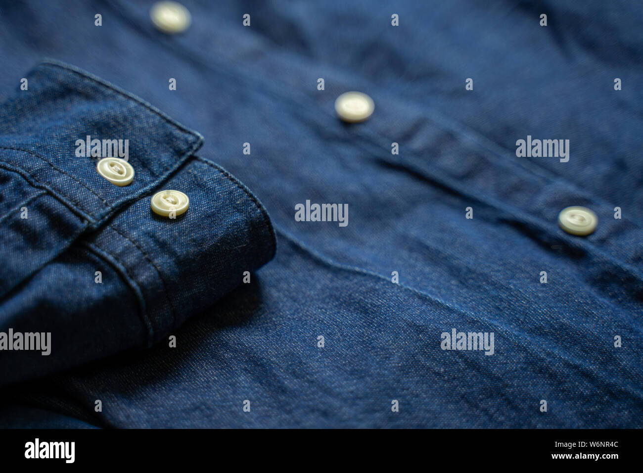 Blue denim shirt cuff with white buttons close-up. Garment background ...